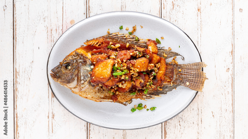 tasty large fried nile tilapia fish with garlic and chili in oval ...