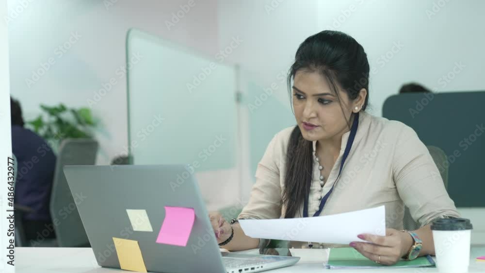 Young serious Indian ethnicity woman working on laptop reading reports ...