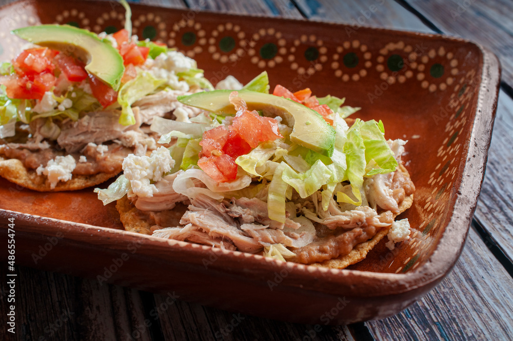 Traditional Mexican food tostadas on a clay or mud plate over a rusic ...