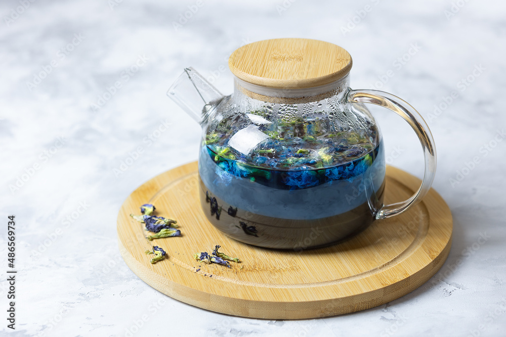 Glass teapot of organic blue anchana on a light table, a place for text ...