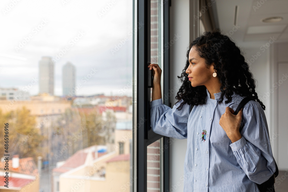 Stylish woman looking out the apartment window Stock Photo | Adobe Stock