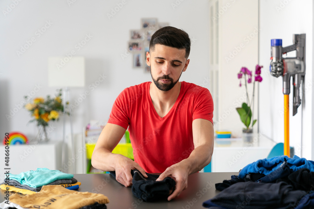 Foto de man folding clothes and placing them in piles do Stock | Adobe Stock