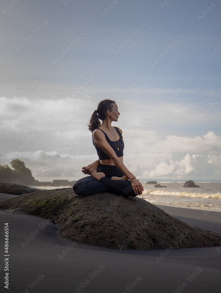 Beach yoga. Asian woman practicing Parivrtta Sukhasana outdoor. Sitting ...