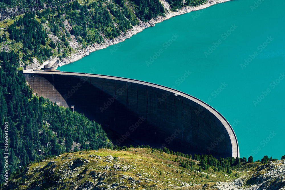 Staumauer eines Wasserspeichers in den Alpen mit türkisblauem Wasser ...