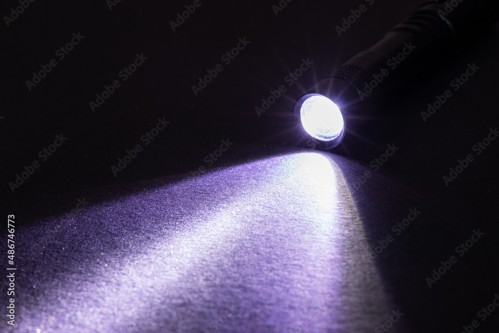 Flashlight and a beam of light in darkness. A modern led lamp with ...