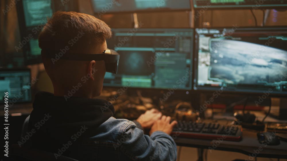 Young man in VR goggles using computer to hack launch of nuclear bomb ...