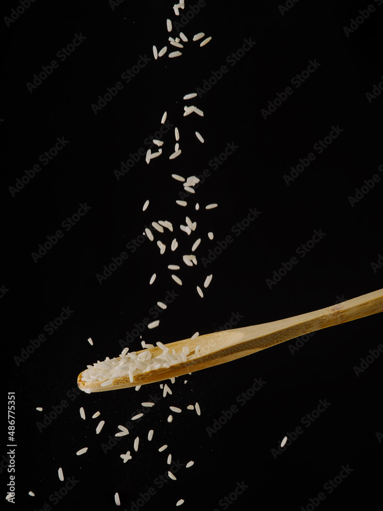 Grains of rice in a frozen flight on a black background fall on a ...