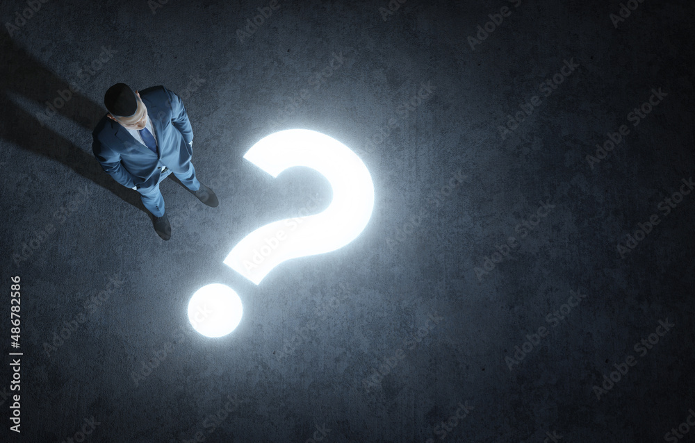 Top view of businessman standing in front of a big glowing question ...