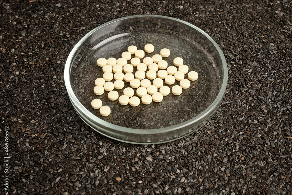 Remedy tablettes in Petri dish on ruberoid textured surface. Small ...