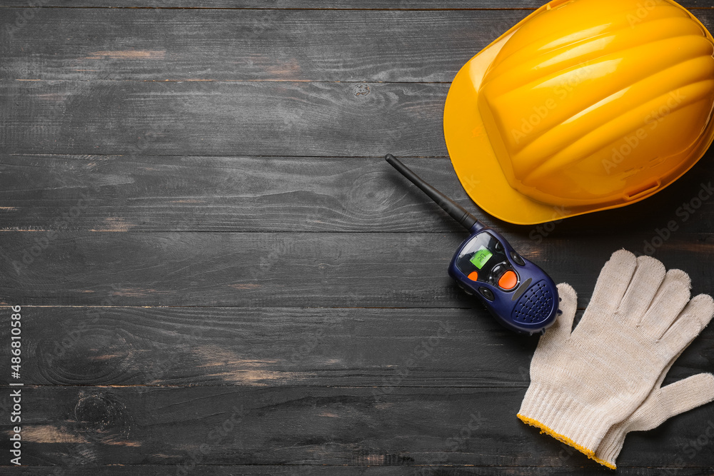Safety hardhat with gloves and radio transmitter on dark wooden ...
