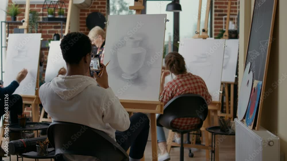 Creative student taking picture of vase sketch on smartphone in art ...