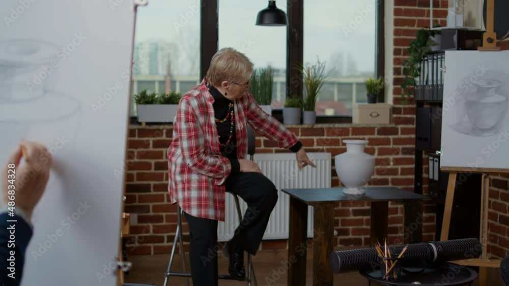 Senior artist teaching diverse group of students drawing skills on ...