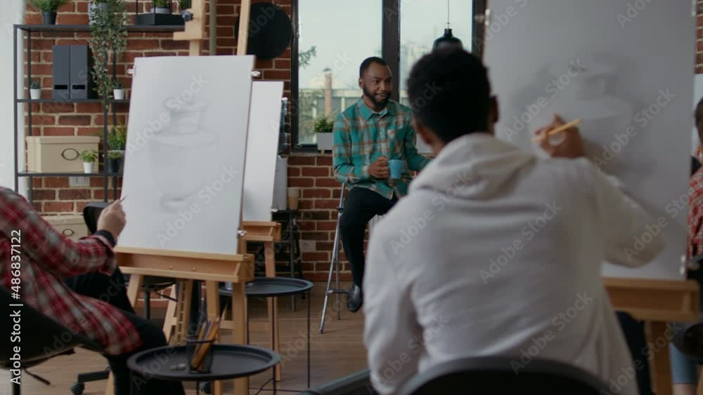 Young man teaching creative people to draw on canvas, explaining ...