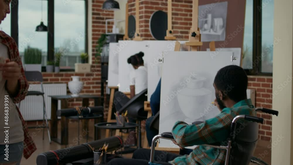 Young man in wheelchair drawing masterpiece with pencil on canvas ...