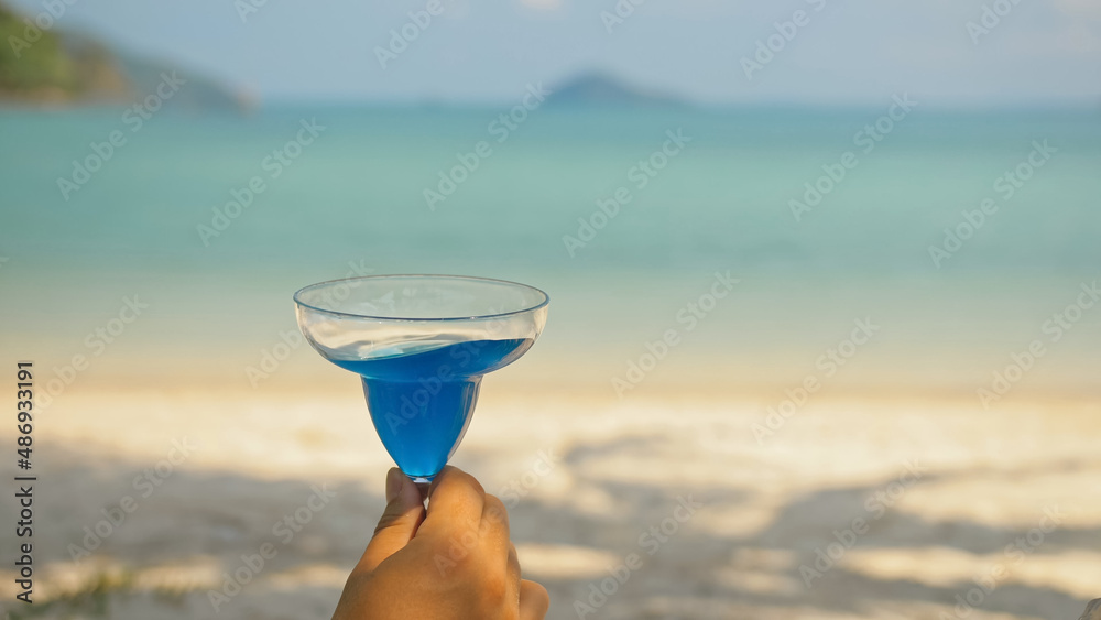 Man hands shake blue cocktails in wineglasses resting on beach in ...