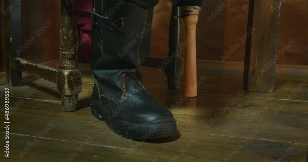 Pirate captain sits on old chair putting wooden leg prosthesis and ...