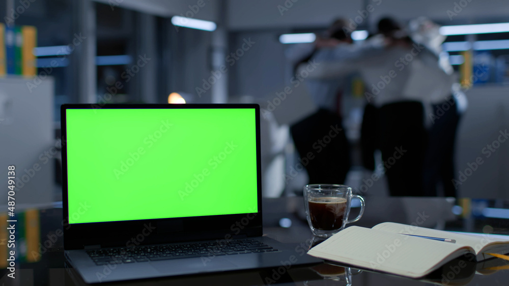 Focus on laptop with green screen on desk in office. Business tean ...