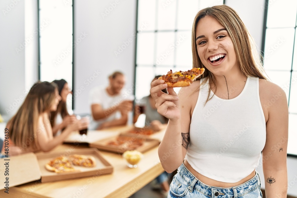 Group of young people eating italian pizza sitting on the table at home ...