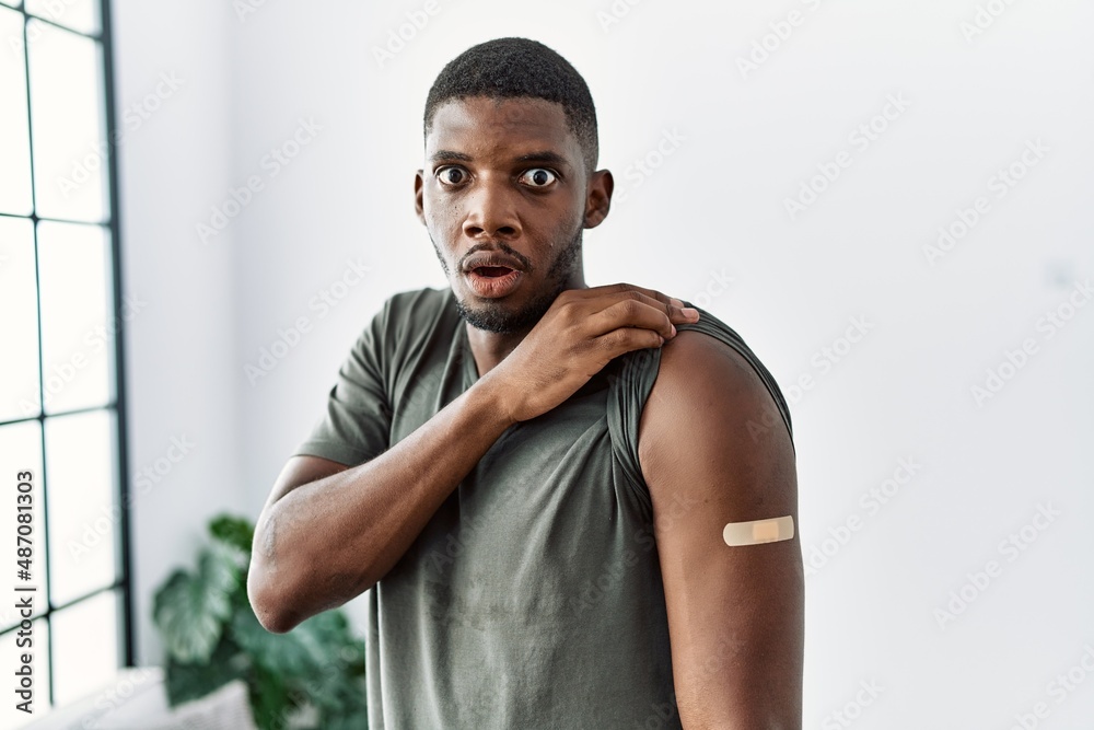 Young african american man getting vaccine showing arm with band aid ...