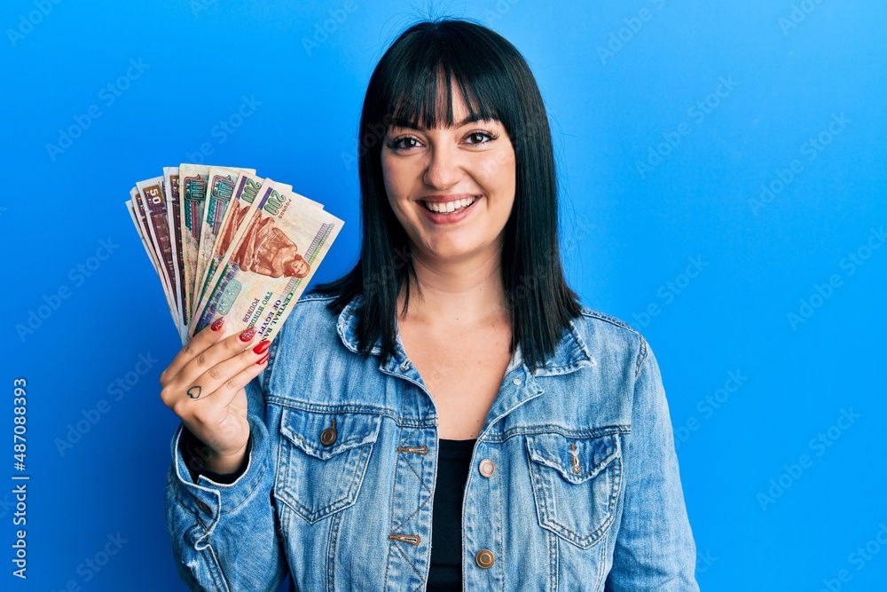 Young hispanic woman holding egyptian pounds banknotes looking positive ...