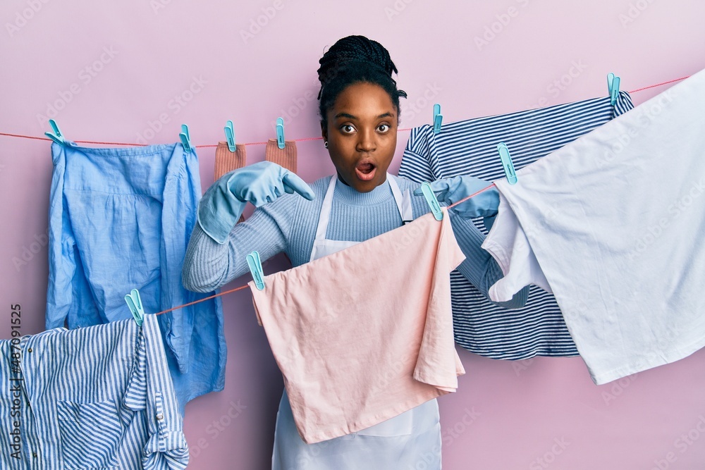 African american woman with braided hair washing clothes at clothesline ...