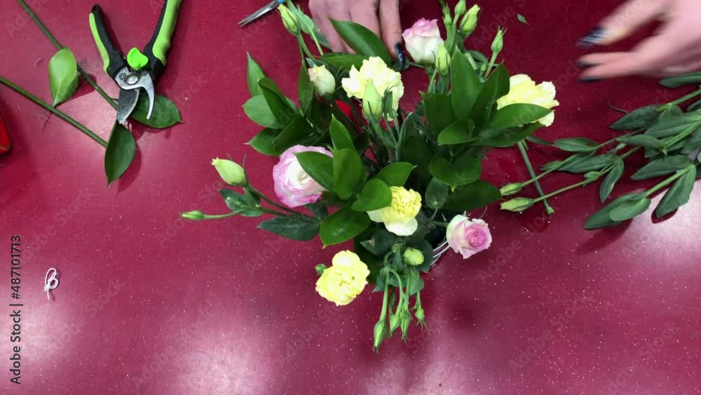 A female florist begins to collect a composition of different flowers ...
