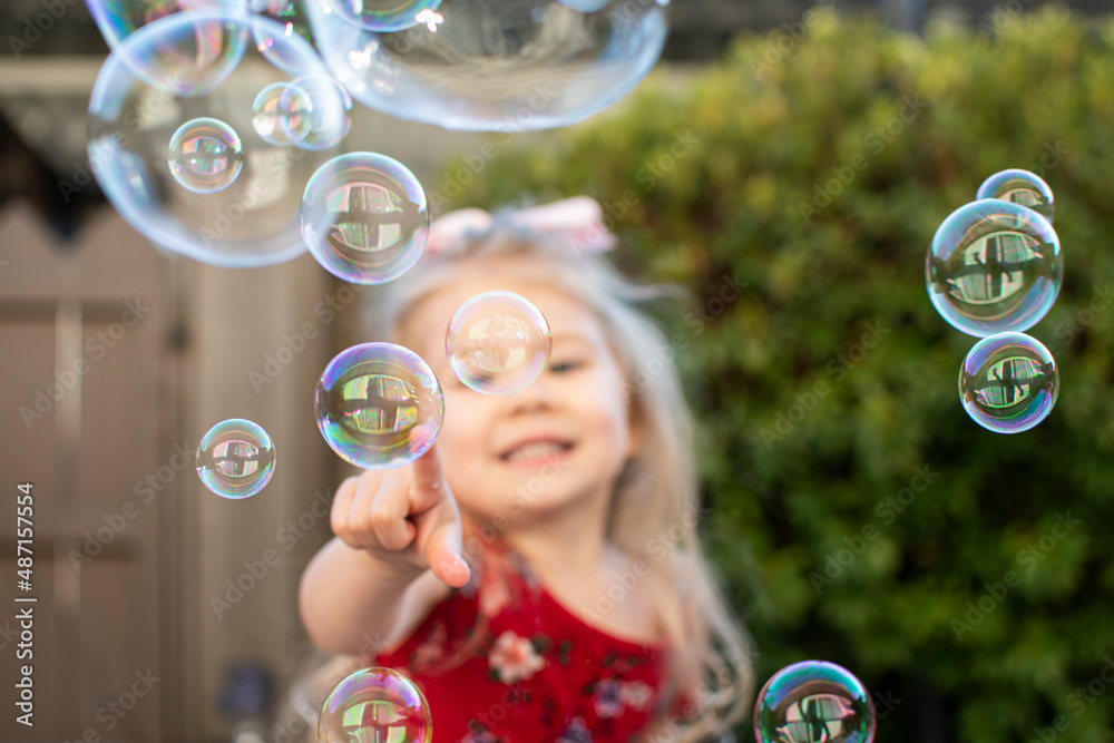 Little girl playing with bubbles. Happy child popping bubbles. Stock ...