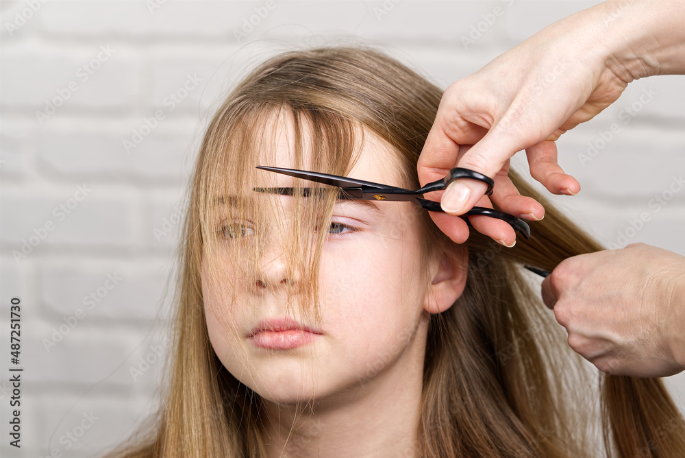 Hairdresser making a hair to cute girl in hair salon. Young girl at ...