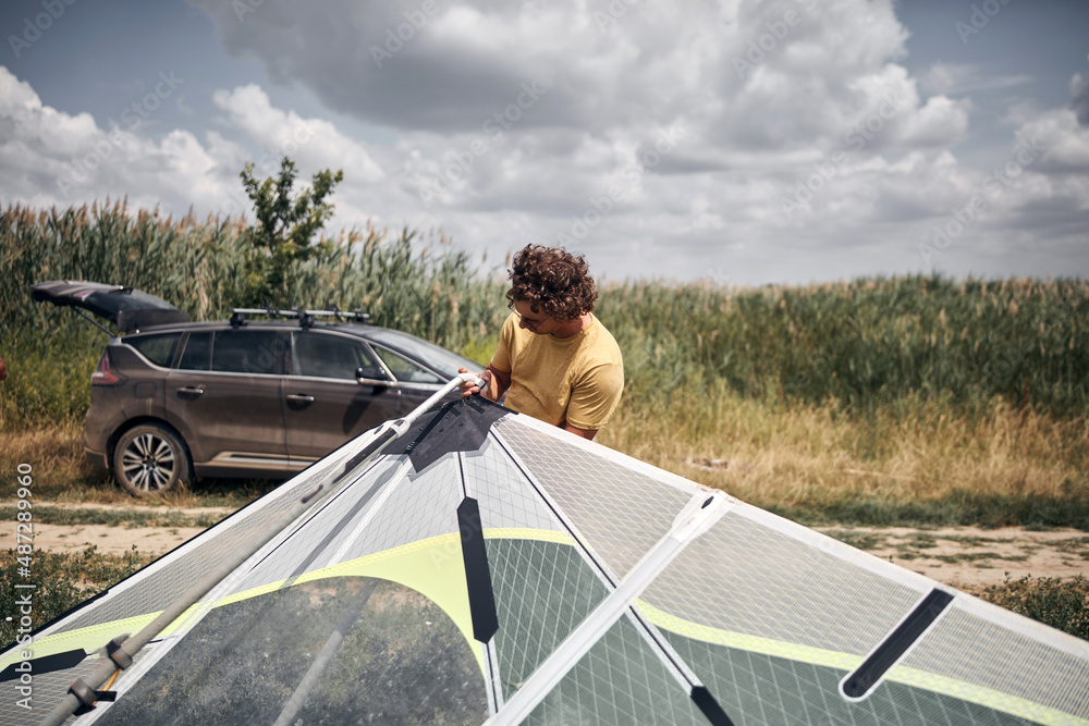 Windsurfer and camper packing and unpacking from a car's roof rack in ...