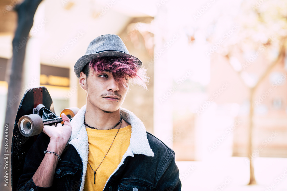 Trendy teenager boy portrait holding skate board and wearing hat ...