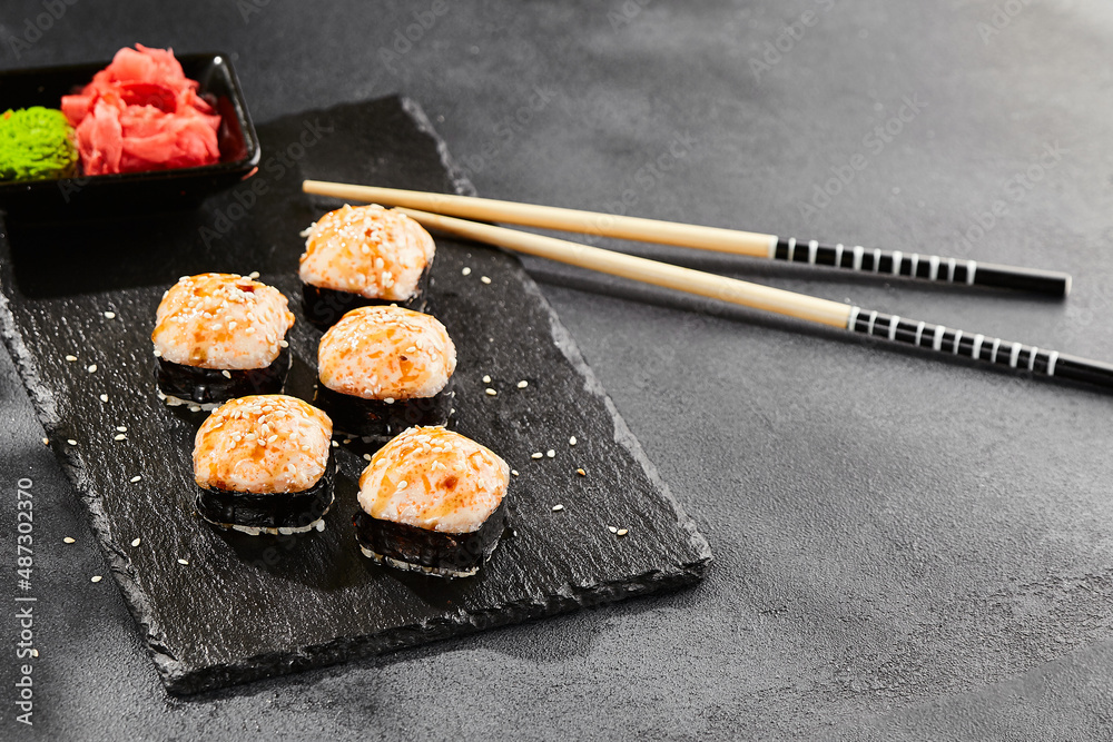 Baked Maki sushi on dark slate. Hot unagi maki with tobiko. Sushi roll ...