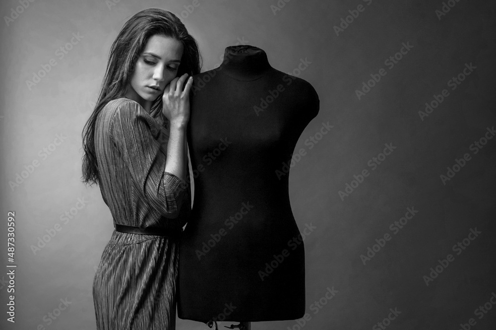 young girl model, fashion designer in her office, leaning on mannequins ...
