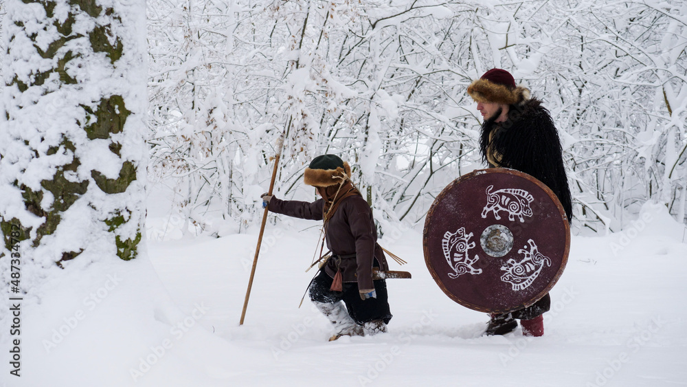Father viking with his son going in the winter forest. Father holding ...