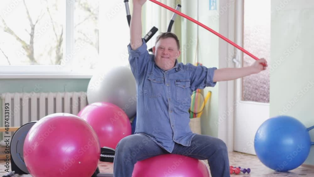 A young, happy man with Down syndrome is engaged in sports exercises ...