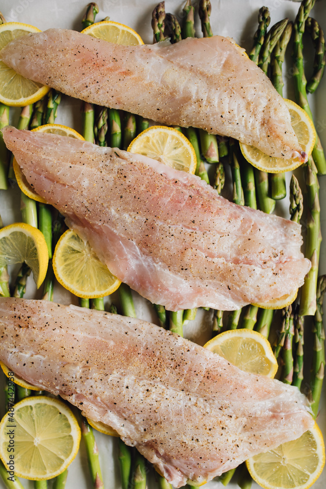 Raw pacific rockfish on a bed of asparagus and lemon wheels, sheet pan ...