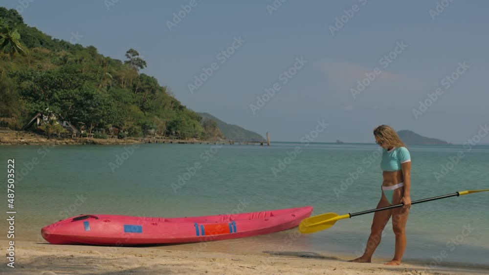 Pretty Young Sportswoman With Sunglasses And Swimsuit Holds Paddle Posing Near Pink Plastic