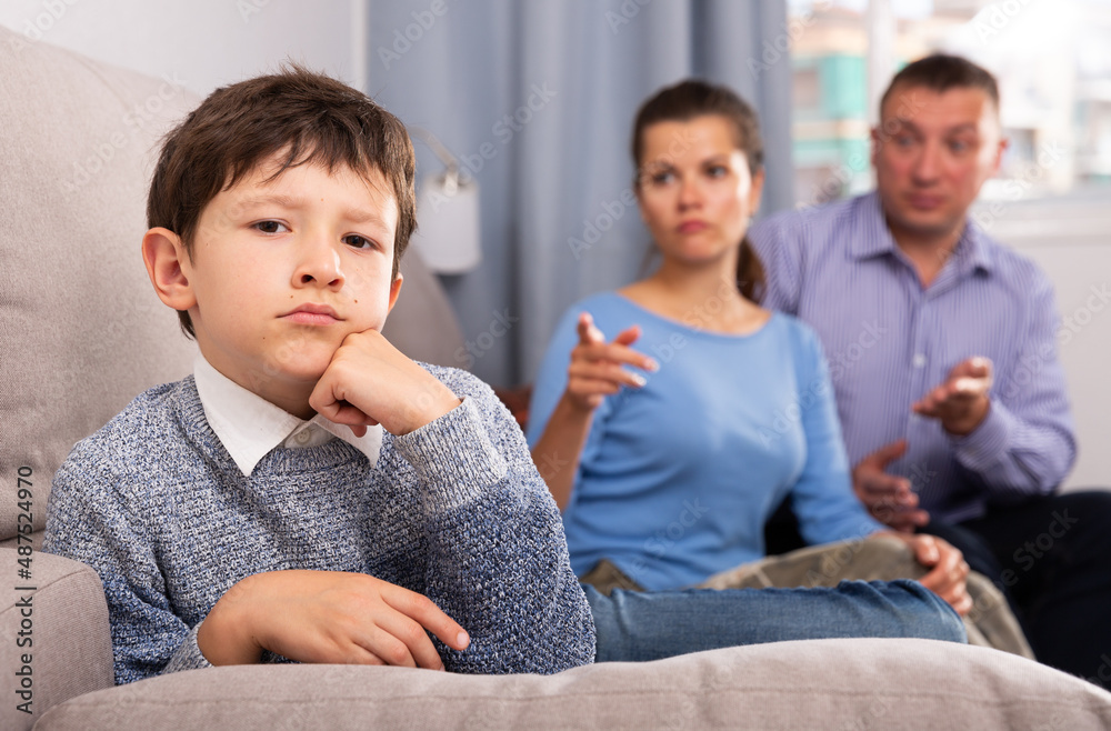 Portrait of upset preteen boy scolded by mother and father at home ...