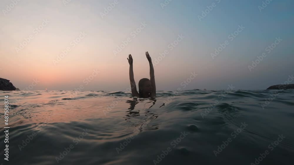 Caucasian girl stands in the sea and throws her arms up. A European ...