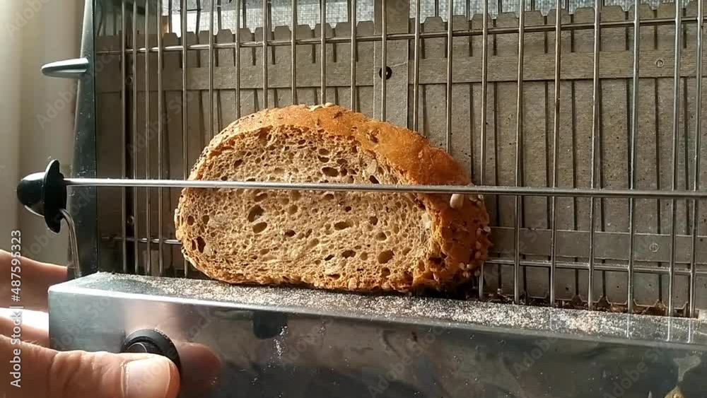 Vertical toaster seen sideways. The holding bar is pulled and a slice ...