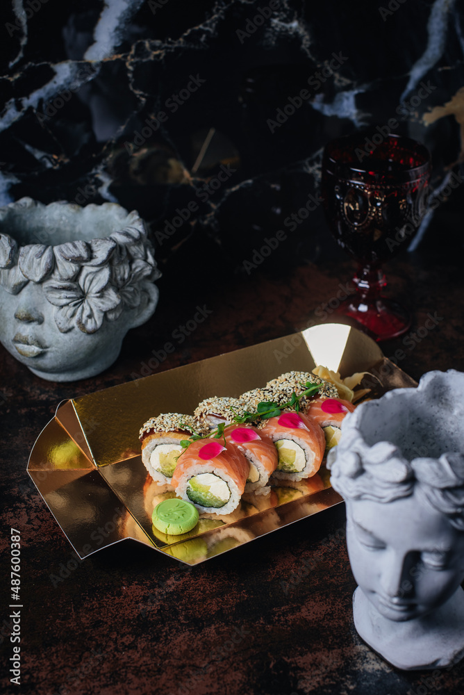 sushi in a box against the background of an ancient Greek statue and a ...