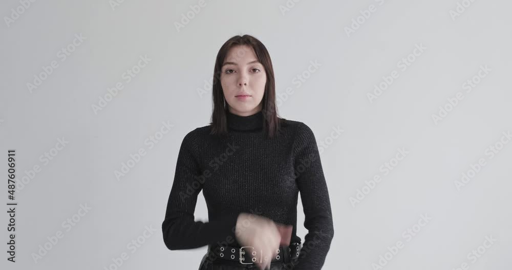young girl in black clothes on white background waving her hands shows ...