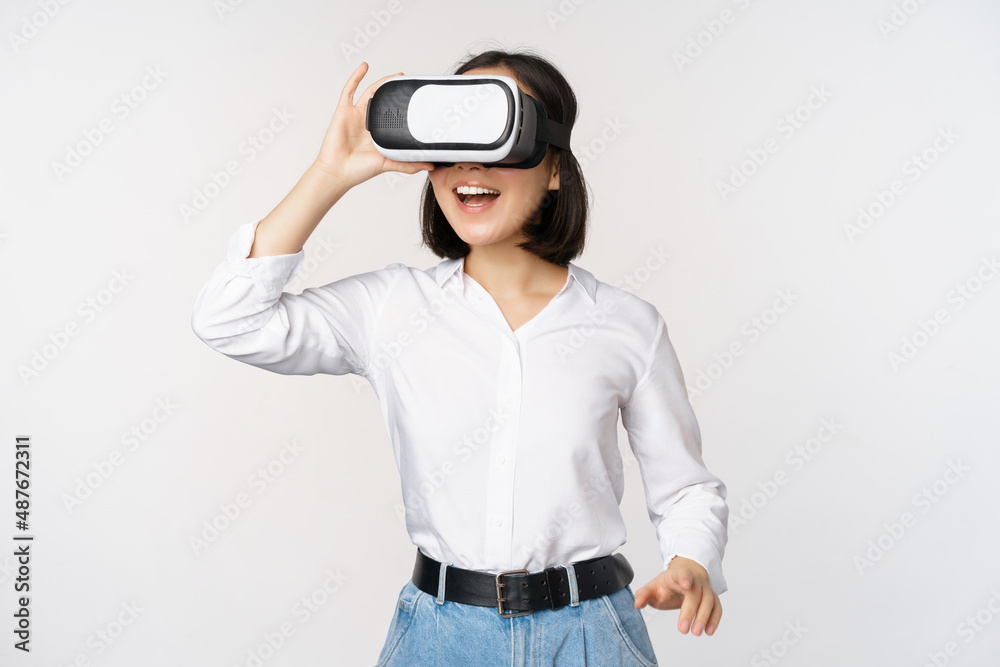 Excited young woman enter virtual reality in her glasses. Asian girl ...