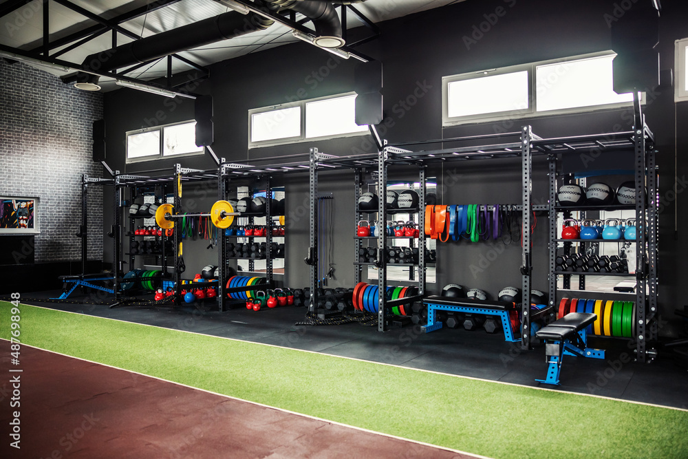 Sports equipment in various colors in a gym with a running track and ...