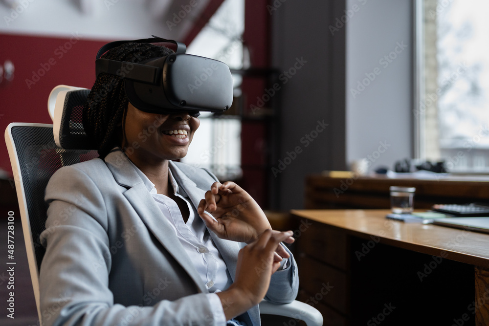 VR training in workplace. Smiling impressed black businesswoman sitting ...