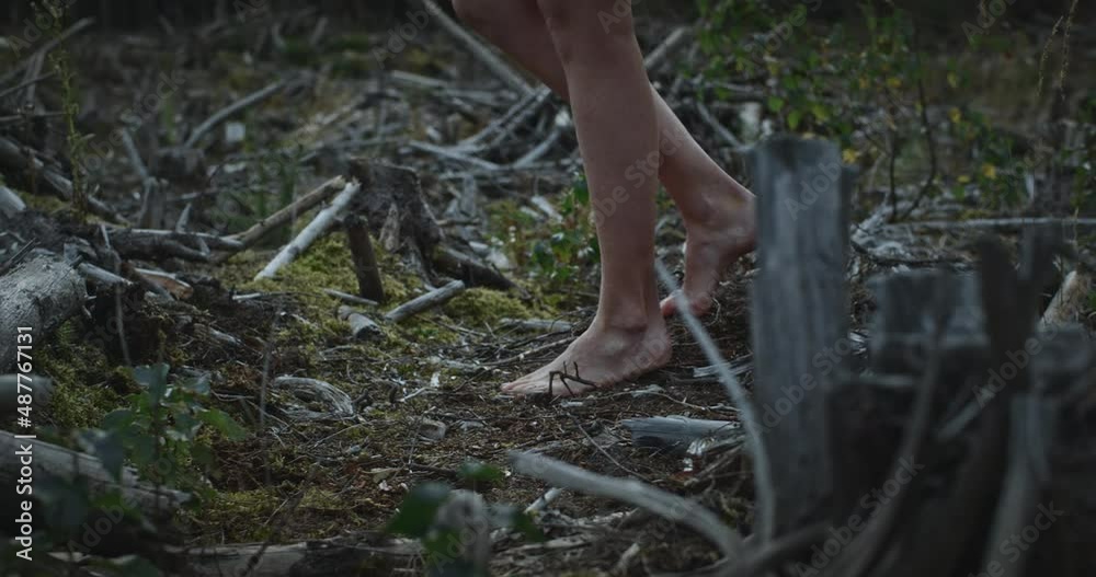 Women's bare feet walk on the ruined forest. Under the feet of women ...