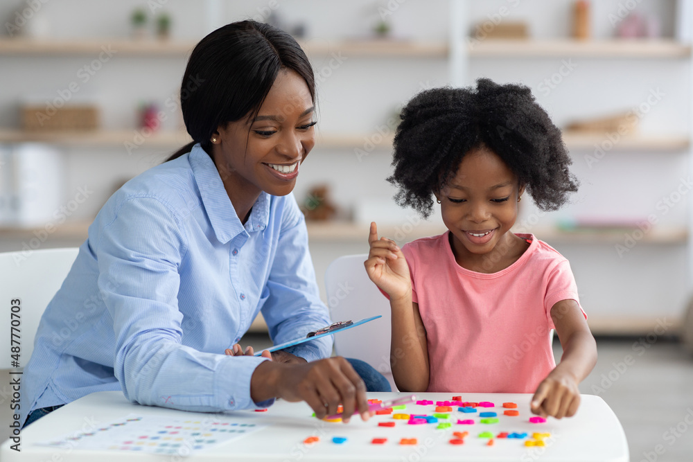 Cheerful black lady teaching little girl alphabet Stock Photo | Adobe Stock