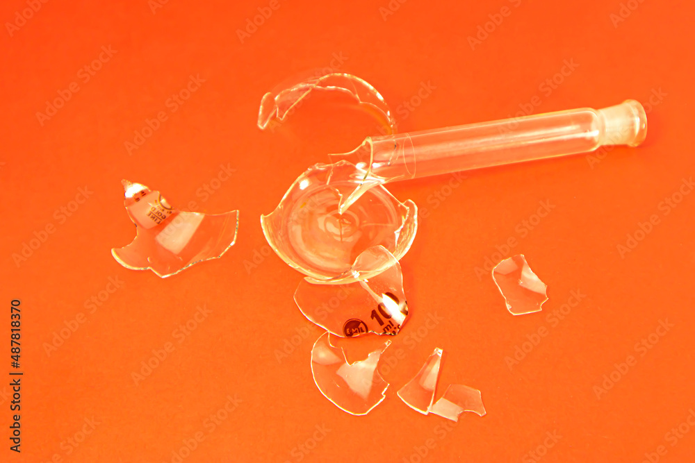 Broken laboratory glass on orange background. Failed lab experiment ...