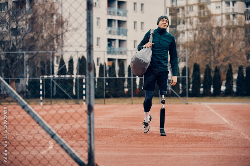 Full length of male athlete with a prosthetic leg coming to practice to ...