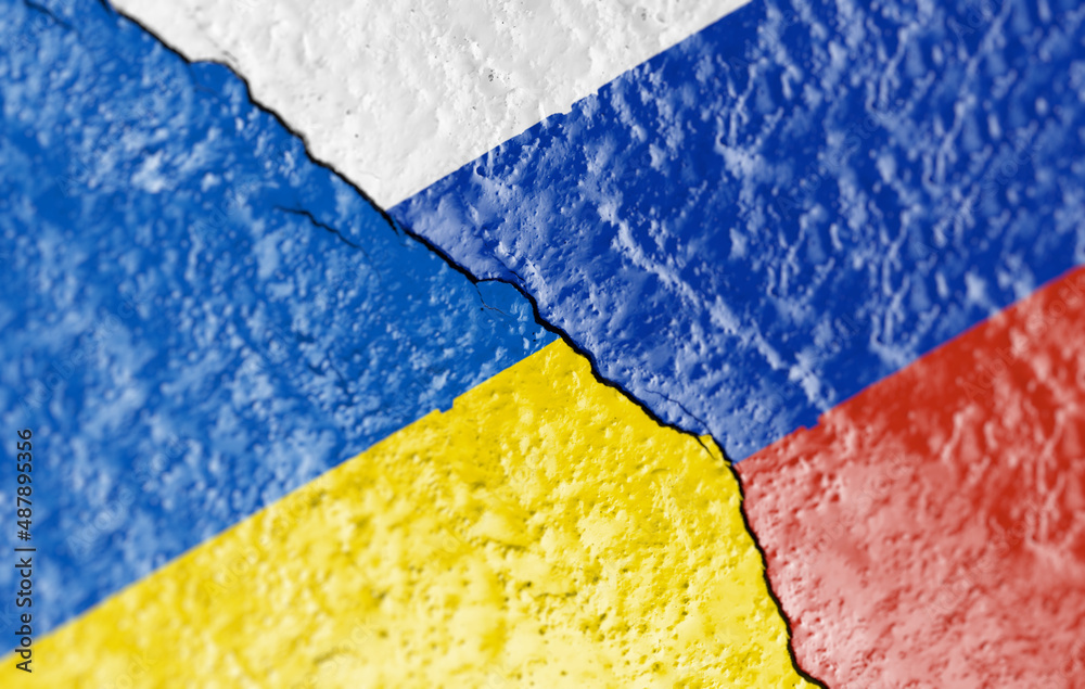 the flags of Ukraine and Russia painted on a ruined wall and divided by ...