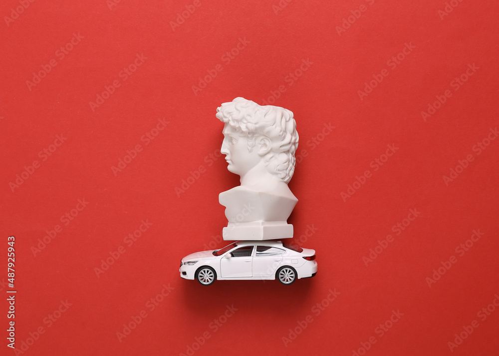 Minimalistic still life. Bust of David on a model car, red background ...